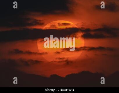 The setting sun is visible behind a new building with a crane in Berlin ...