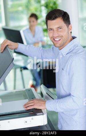 Young man employee working at copying machine in the office Stock Photo ...
