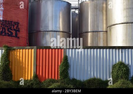 Stainless steel cylindrical industrial silos graffiti painted in bright ...