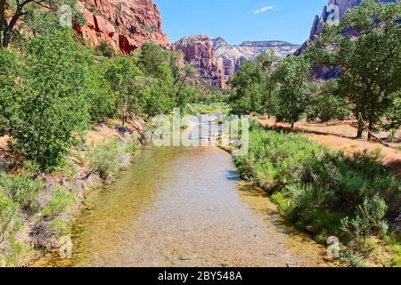 A wide but shallow river flowing in the shadow of a high mountain ...