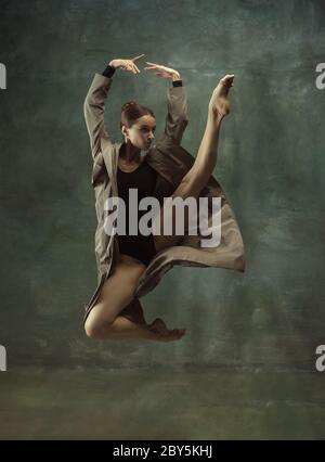 Stylish young woman dancer in pink coat posing against blue background ...