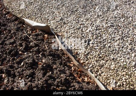 Metal edging separating dirt and different colors of gravel in a park ...