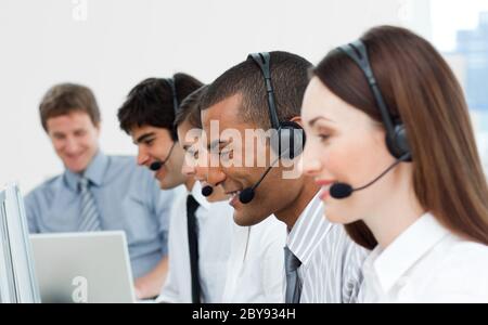 Multi-ethnic customer service agents working in a call center against a ...