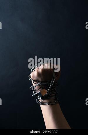 Fist of Hand are chained in chains on the black background, concept of ...