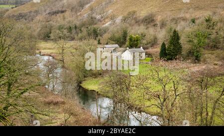 Scenic view of small farm located on green grassy meadow in valley near ...