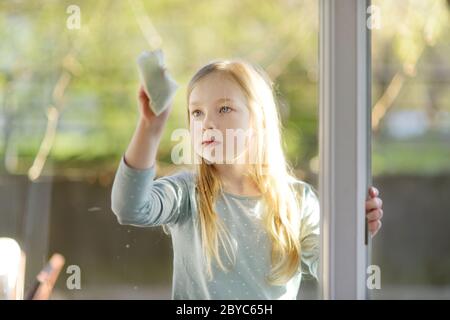 Little girl washing a window. Kids clean the house. Children help at ...