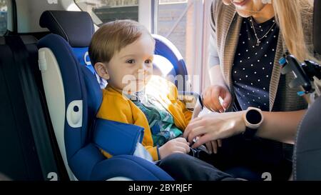 happy mother fastening toddler kid in baby car seat Stock Photo - Alamy