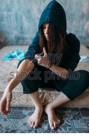 Female junkie with a syringe doing an injection dose in the arm ...