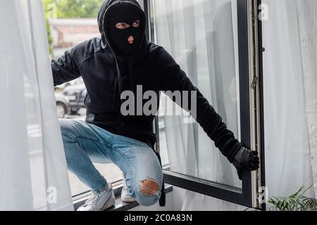 Selective focus of robber in balaclava holding dollars near table Stock ...