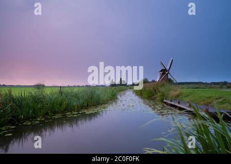 charming windmill by river at rainy sunrise, Holland Stock Photo - Alamy