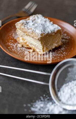 cremeschnitte or cremsnit cake on a square black stone tile texture ...