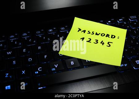password written on a sticky note and taped to the laptop on a wooden ...