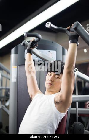 Man works out in gym and performs set of exercises to stretch leg ...