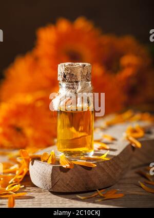 aromatherapy essential oil with fresh marigold flowers on white wooden ...