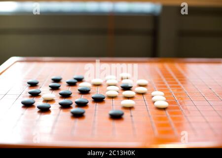 black and white stones on a ‘GO’ board made from wood on white ...