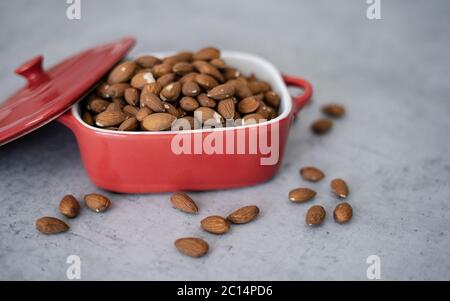 Almonds in red porcelain bowl on wooden table. Almond concept with ...