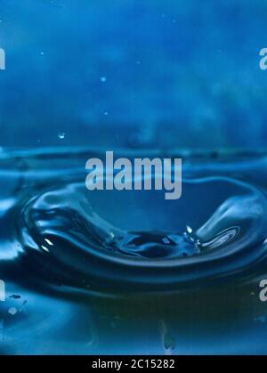 Water droplets falling on and bouncing off a pool of water, leaving ...