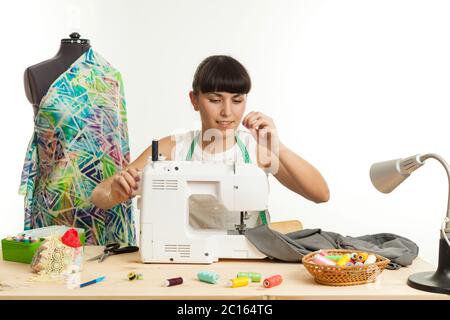 Fashion designer sews clothes on a sewing machine. Dressmaker works in ...