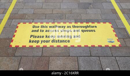 Signs and stickers on pavement to guide pedestrians along ...