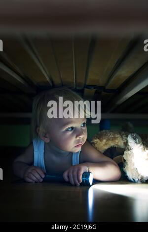 Sad little boy hiding under slide on children playground at ...