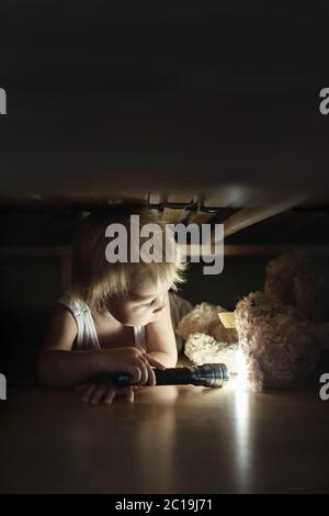 Sad little boy hiding under slide on children playground at ...