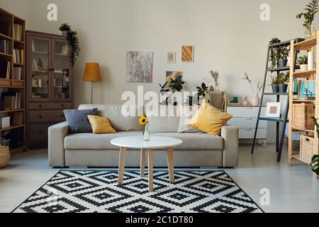 Comfortable sofa, coffee table, pictures and houseplants in interior of ...