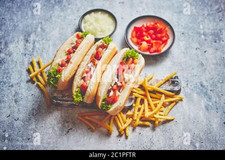 Assortment of three tasety hot dogs, placed on wooden cutting board ...