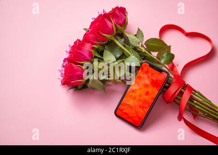 Pink roses bouquet with hart shaped bow and mobile phone with copy ...