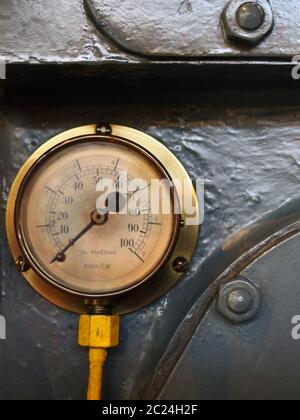 an old round pressure meter with numbers on the gauge on a rusty metal ...