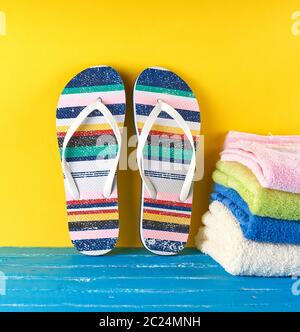pair of female beach slippers and a towels on a blue background ...
