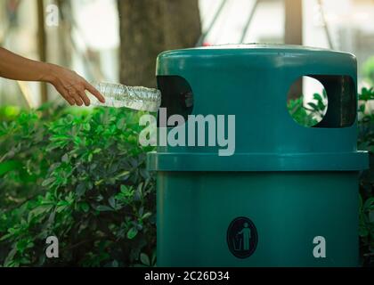 People hand throwing empty water bottle in recycle bin. Blue plastic recycle bin. Man discard ...