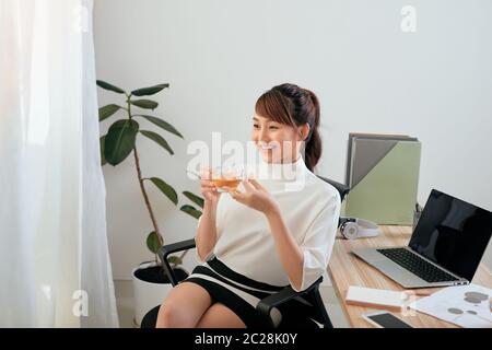 Beautiful Vietnamese business lady drinking coffee and reading e-mails ...