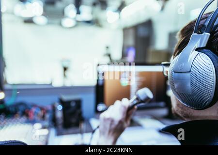 Young man in headphones, with microphone and mobile phone singing on ...