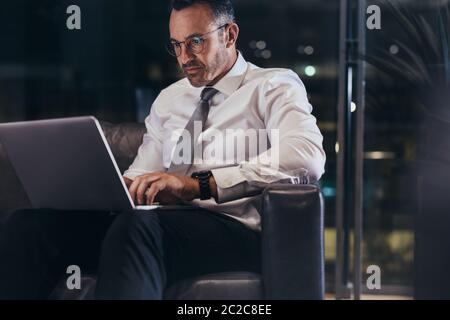 A man is working on a laptop at the airport while waiting to board the ...