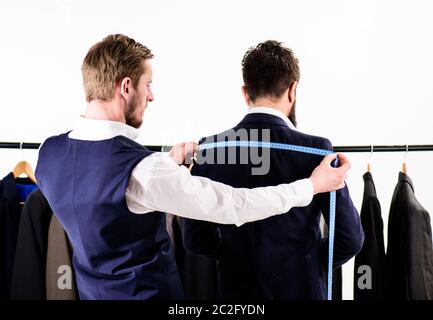 Businessman, client stand near hanger with suits while tailor working ...