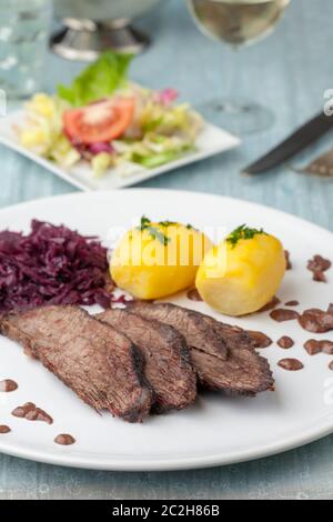german sauerbraten with red cabbage on a plate Stock Photo - Alamy