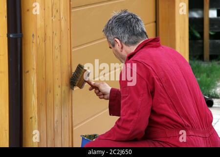 Man paints wooden boards with paint brush. Carpenter cabinetmaker ...