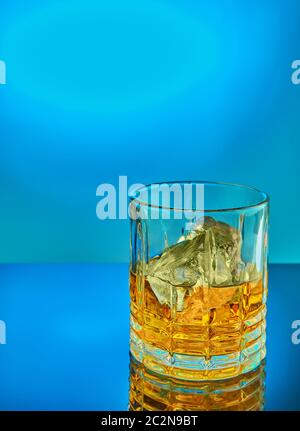 Brandy glass with ice on blue background Stock Photo - Alamy