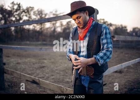 Cowboy checks his revolver before gunfight on ranch, western. Vintage ...