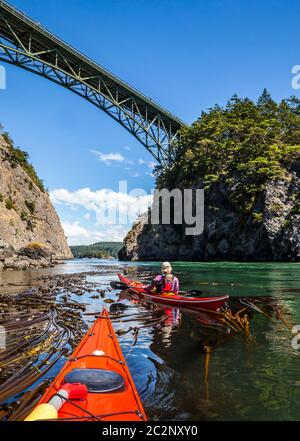 USA, Washington State, Woman sea kayaker in rock garden in moderate ...