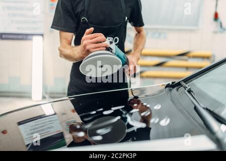 Male person with polishing machine prepares to restore the paint of car ...