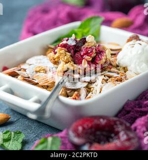 sweet homemade yogurt with fresh plum slices in a glass on a wooden ...