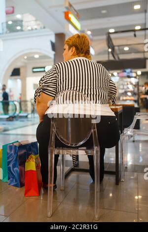 Fat woman sitting at the table, back view Stock Photo - Alamy