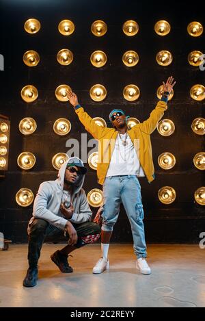 Rappers in caps dance on stage with spotlights Stock Photo - Alamy