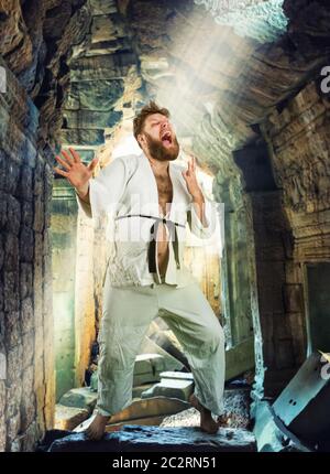 Karate man in an old kimono and black belt training side kick at the ...