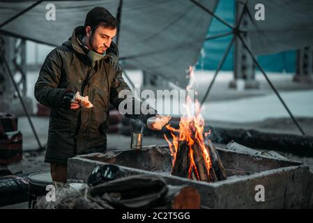 Stalker cooking food on fire, dog on background. Post apocalyptic ...