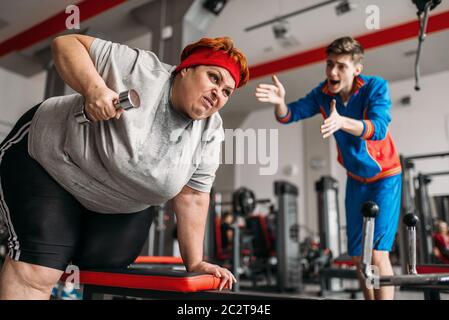 Instructor forces fat woman to exercise, hard workout in gym. Calories ...