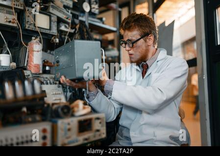 Crazy scientist in glasses holds electrical device in laboratory ...
