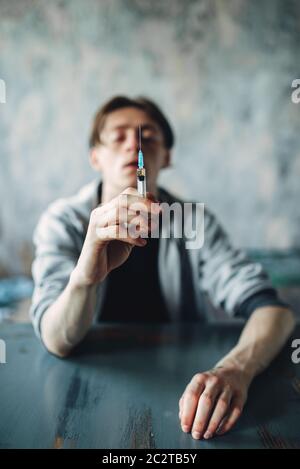 Male druggy with syringe in hand sleeping in bed after dose. Drug ...