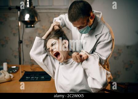 Psychiatrist with syringe makes a sedative injection to crazy female ...